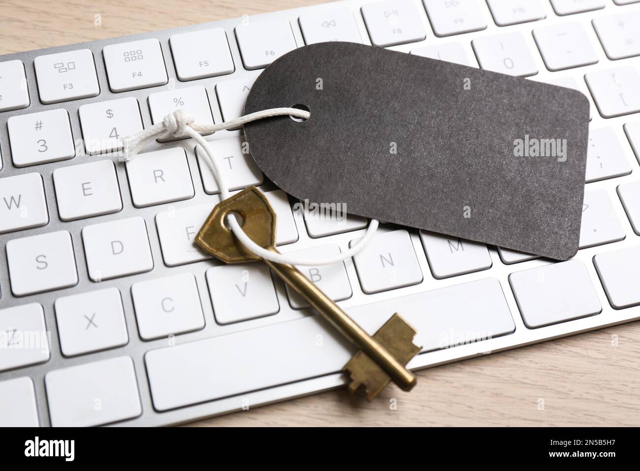 Key with blank tag and computer keyboard on table, closeup. Keyword ...