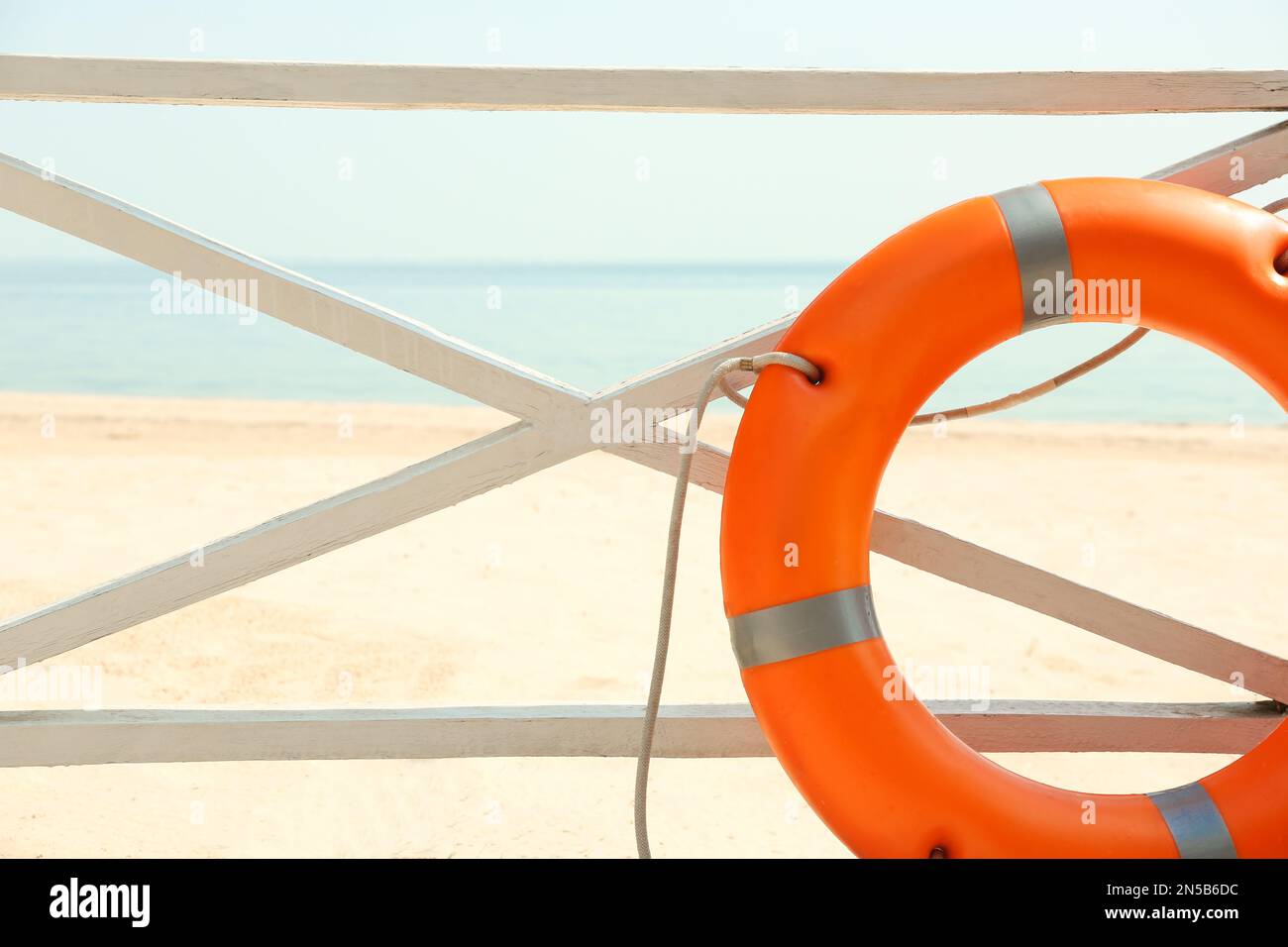 Orange life buoy near wooden railing on beach, closeup. Emergency ...