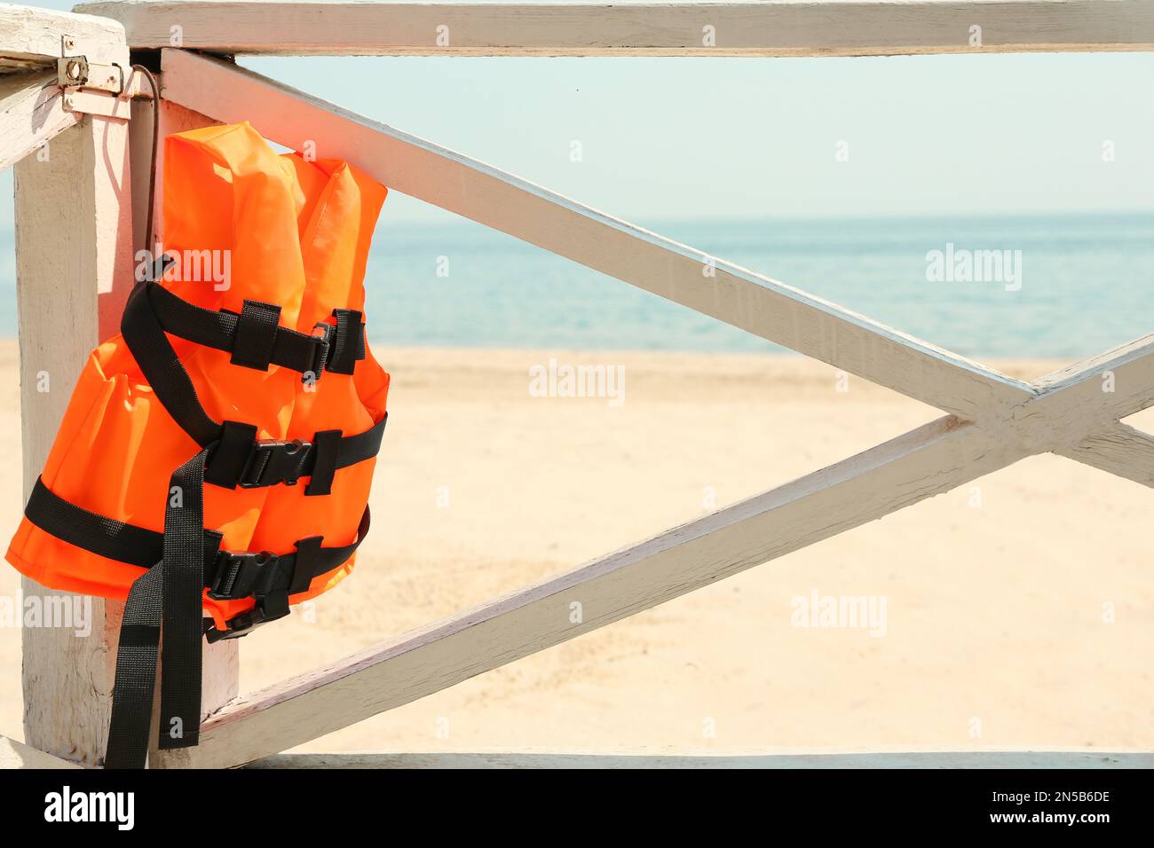 Orange life jacket hanging on wooden railing. Emergency rescue ...