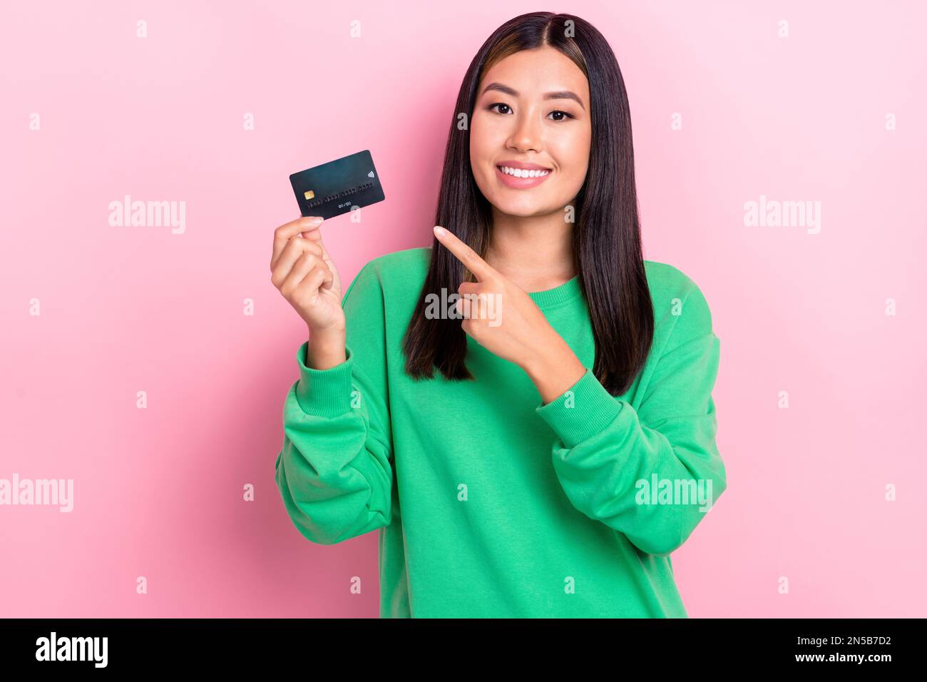 Portrait of charming cheerful girl indicate finger hand hold debit card ...