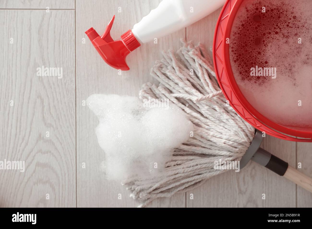 Bucket, mop and bottle of cleaning product on floor indoors, flat lay ...