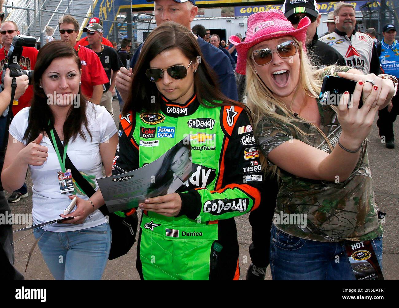 Danica Patrick, middle, signs an autograph for a fan, left, as another ...