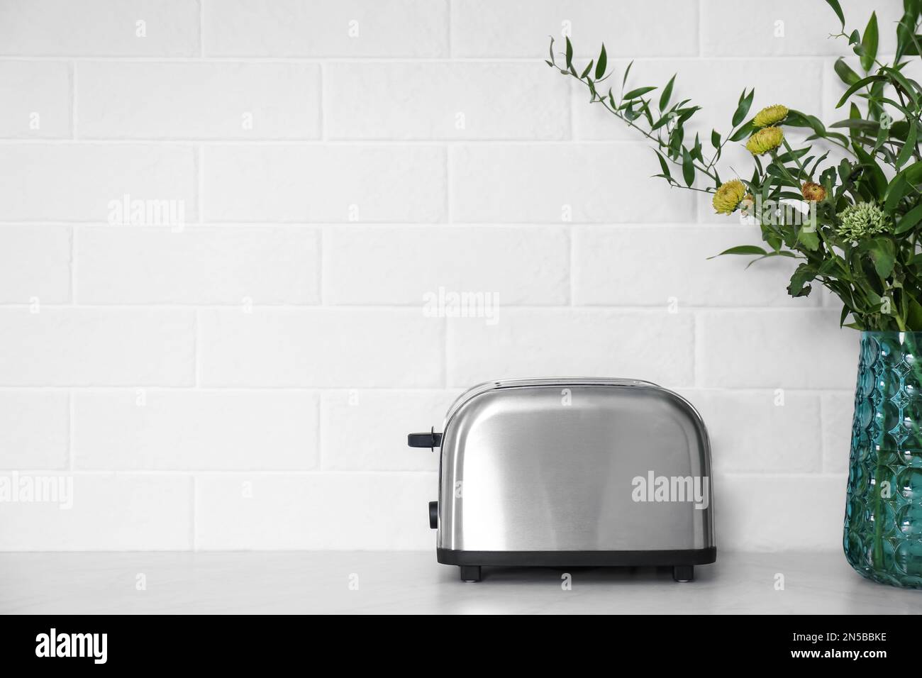 Modern stainless steel toaster on countertop in kitchen. Space for text ...