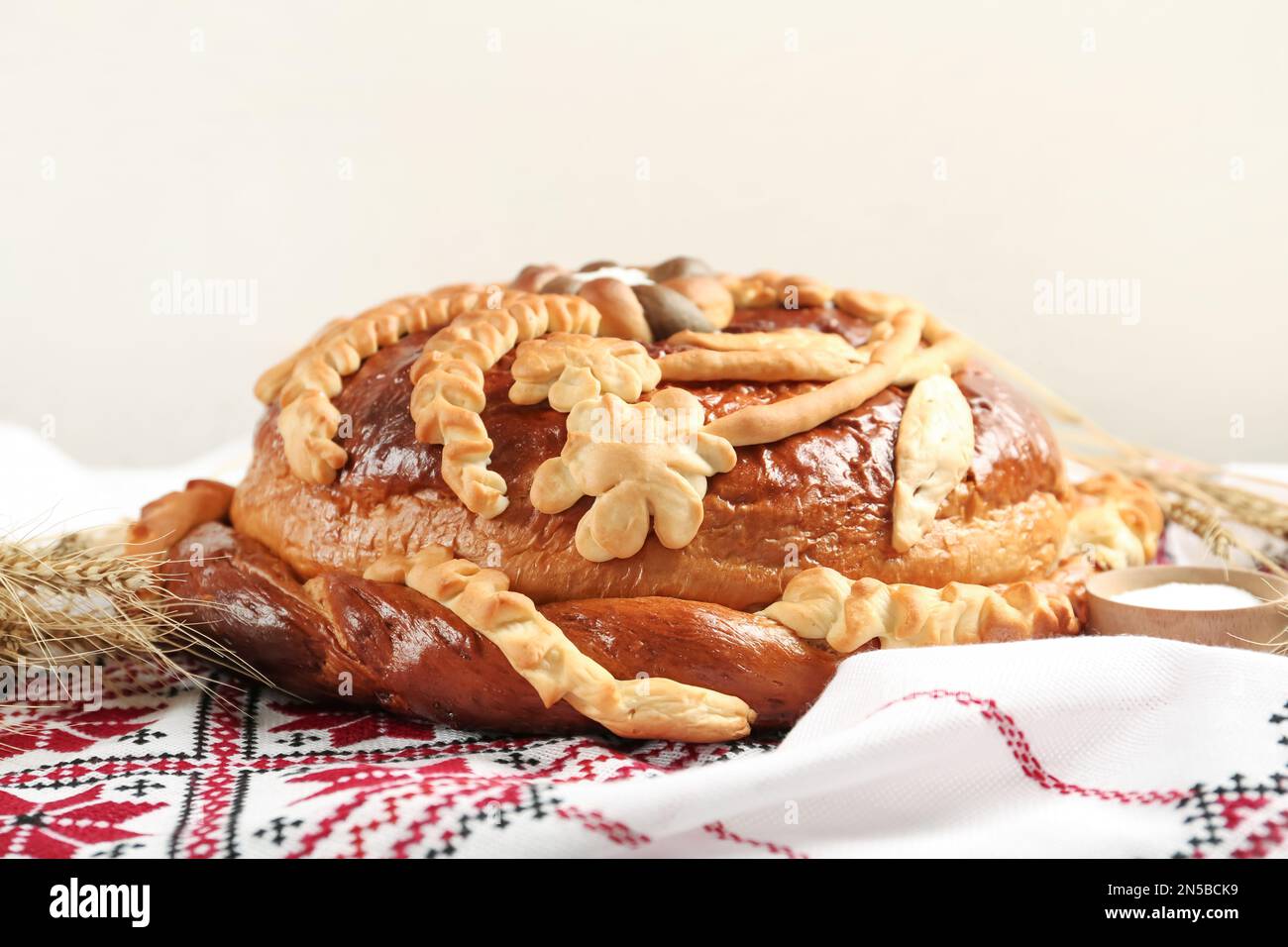 Rushnyk with korovai on light background, closeup. Ukrainian bread and ...