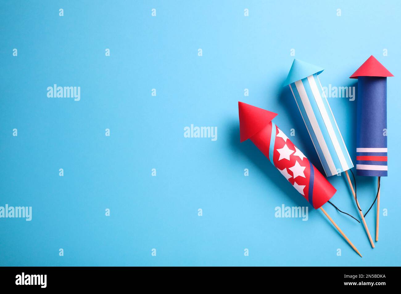 Firework rockets on light blue background, flat lay. Space for text ...