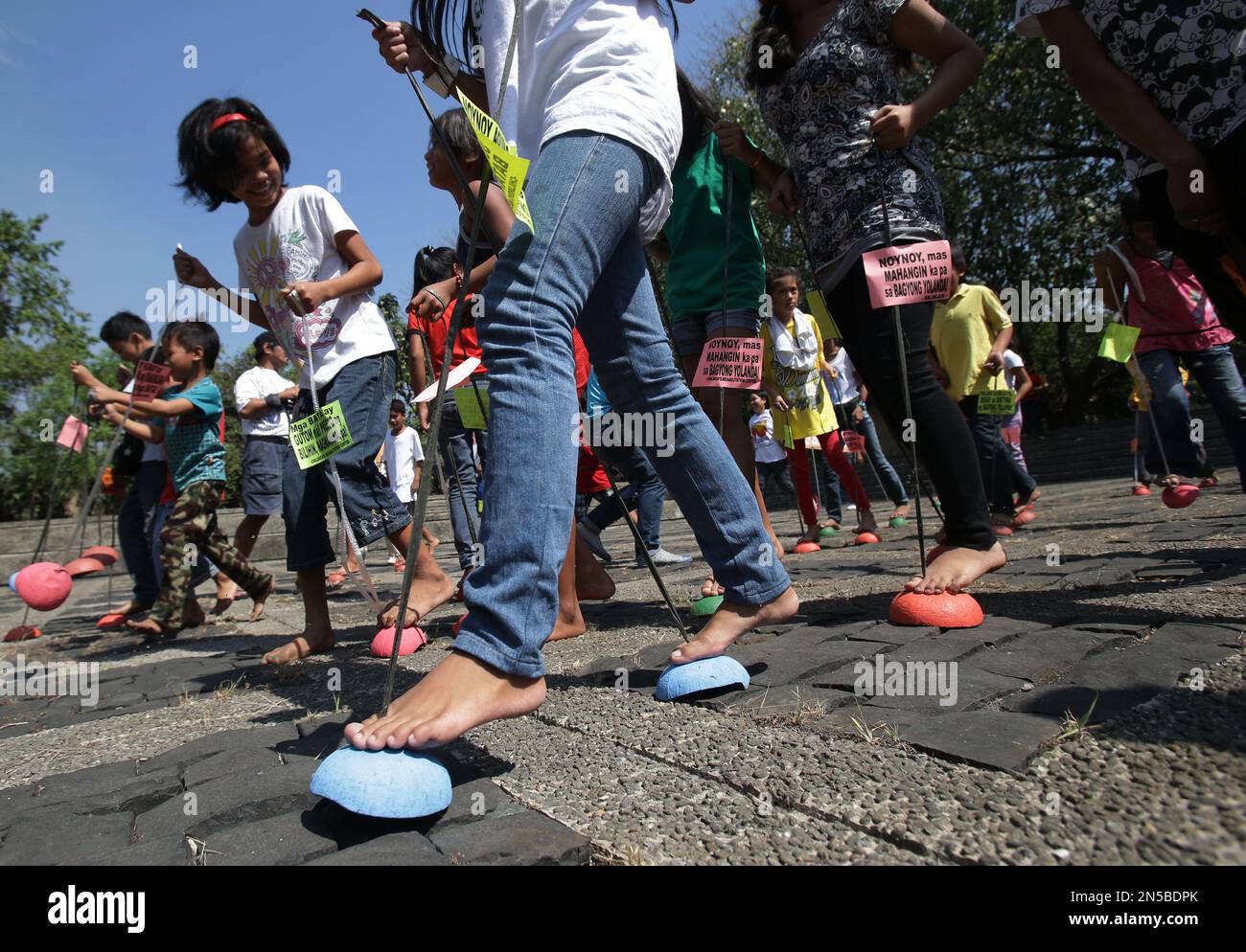Filipino children walk using coconut husks as stilt-like footwear ...