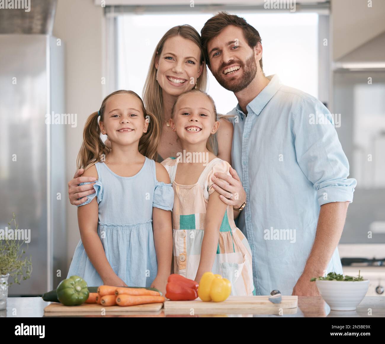 Portrait of parents and children cooking with vegetables in kitchen for ...