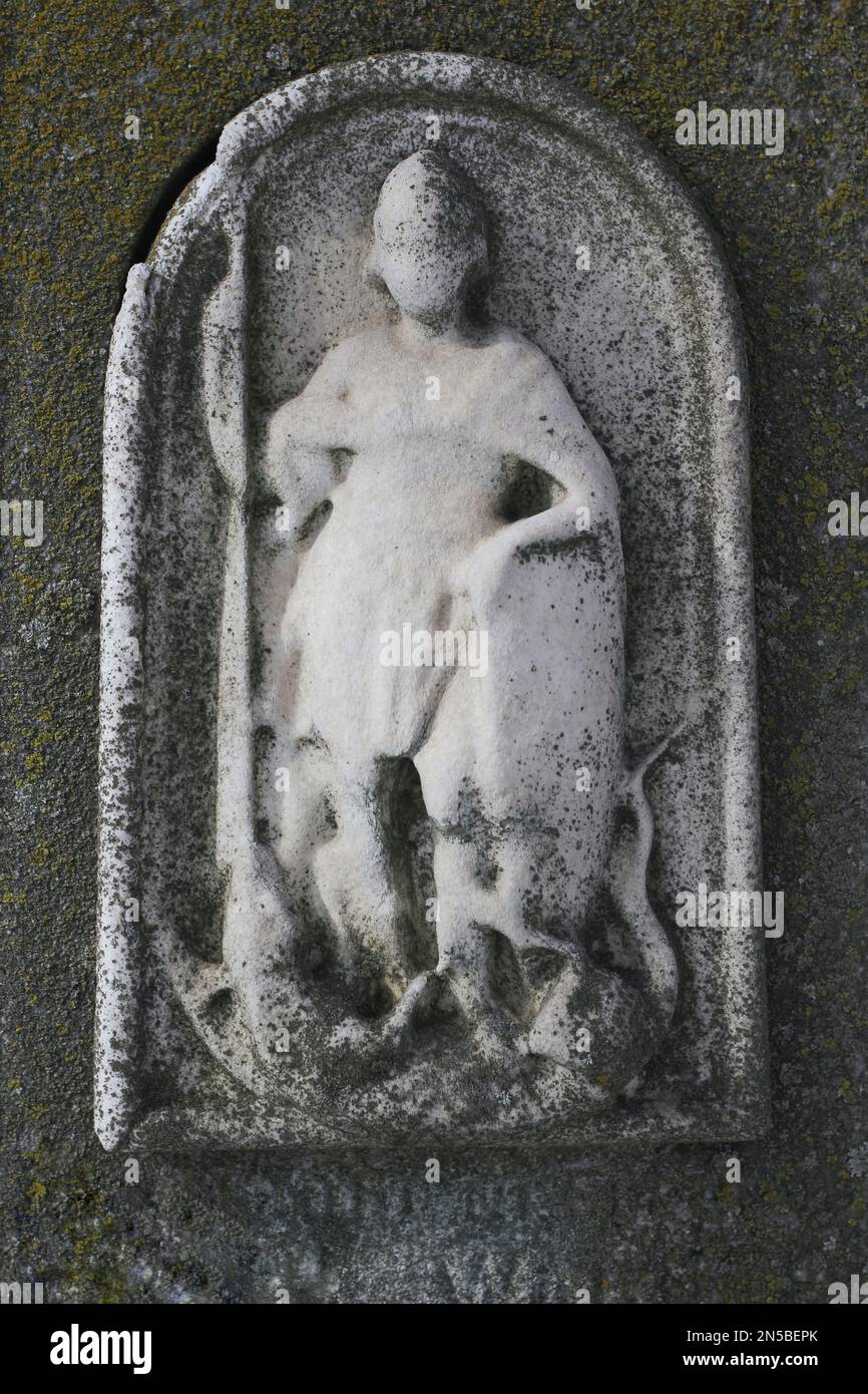 A worn and weathered natural stone statue of Saint Michael the ...