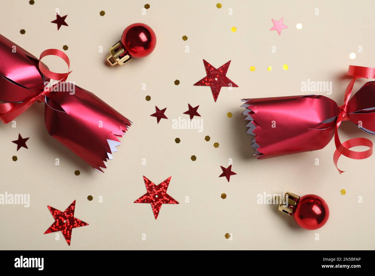 Open red Christmas cracker and decorations with shiny confetti on beige ...