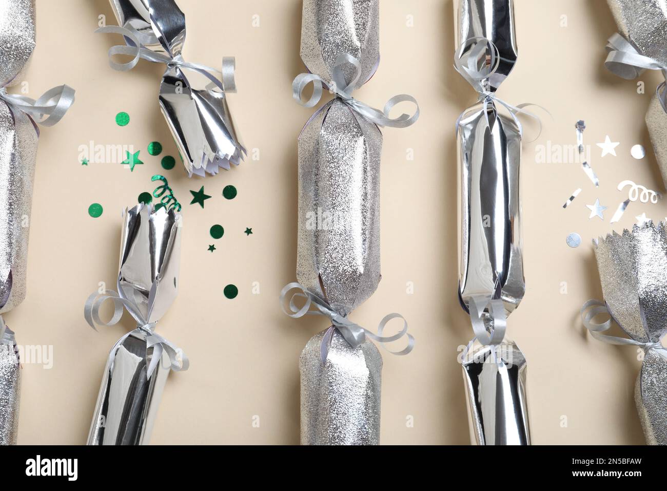 Open and closed silver Christmas crackers with shiny confetti on beige ...