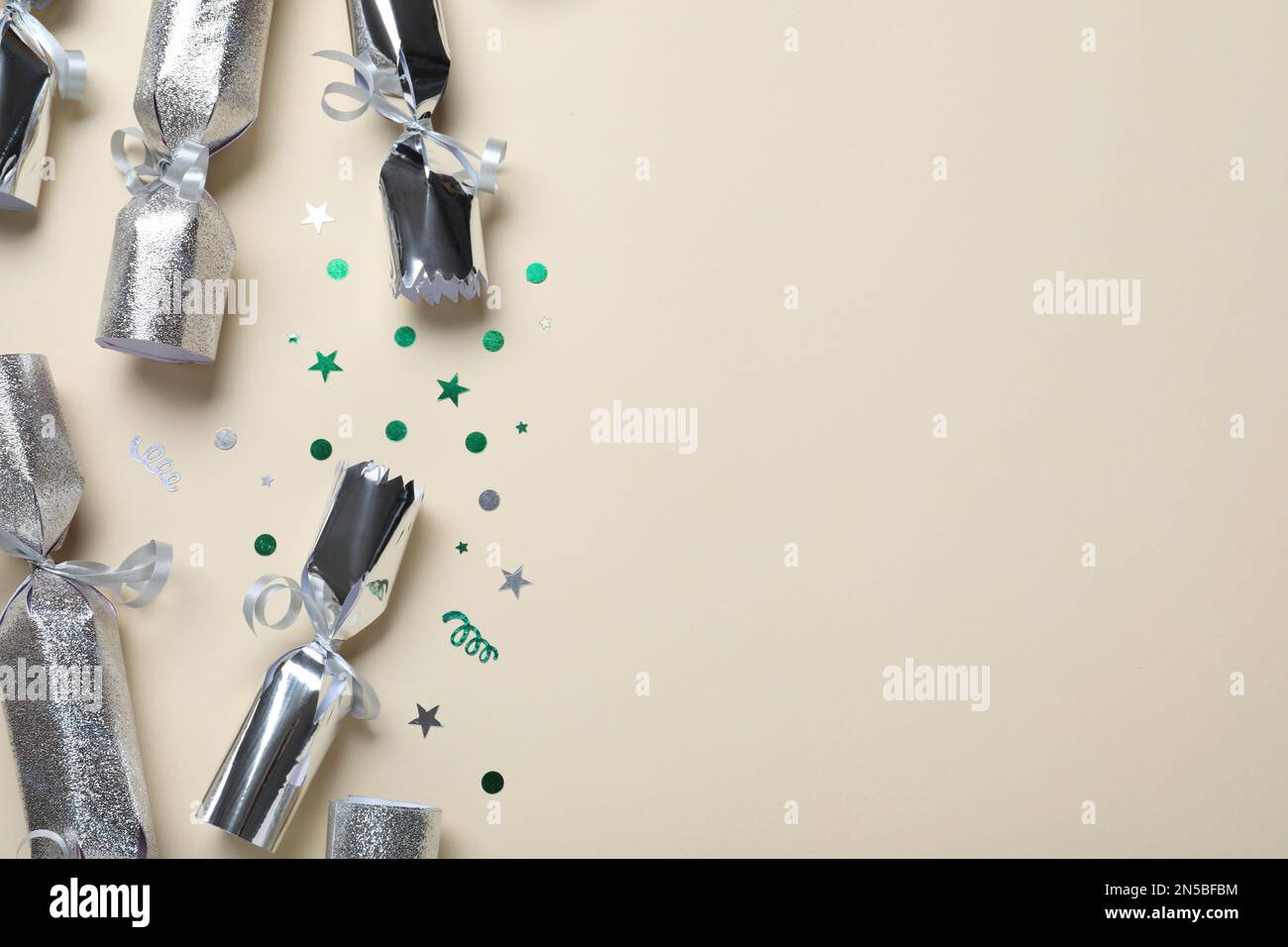 Open and closed silver Christmas crackers with shiny confetti on beige ...