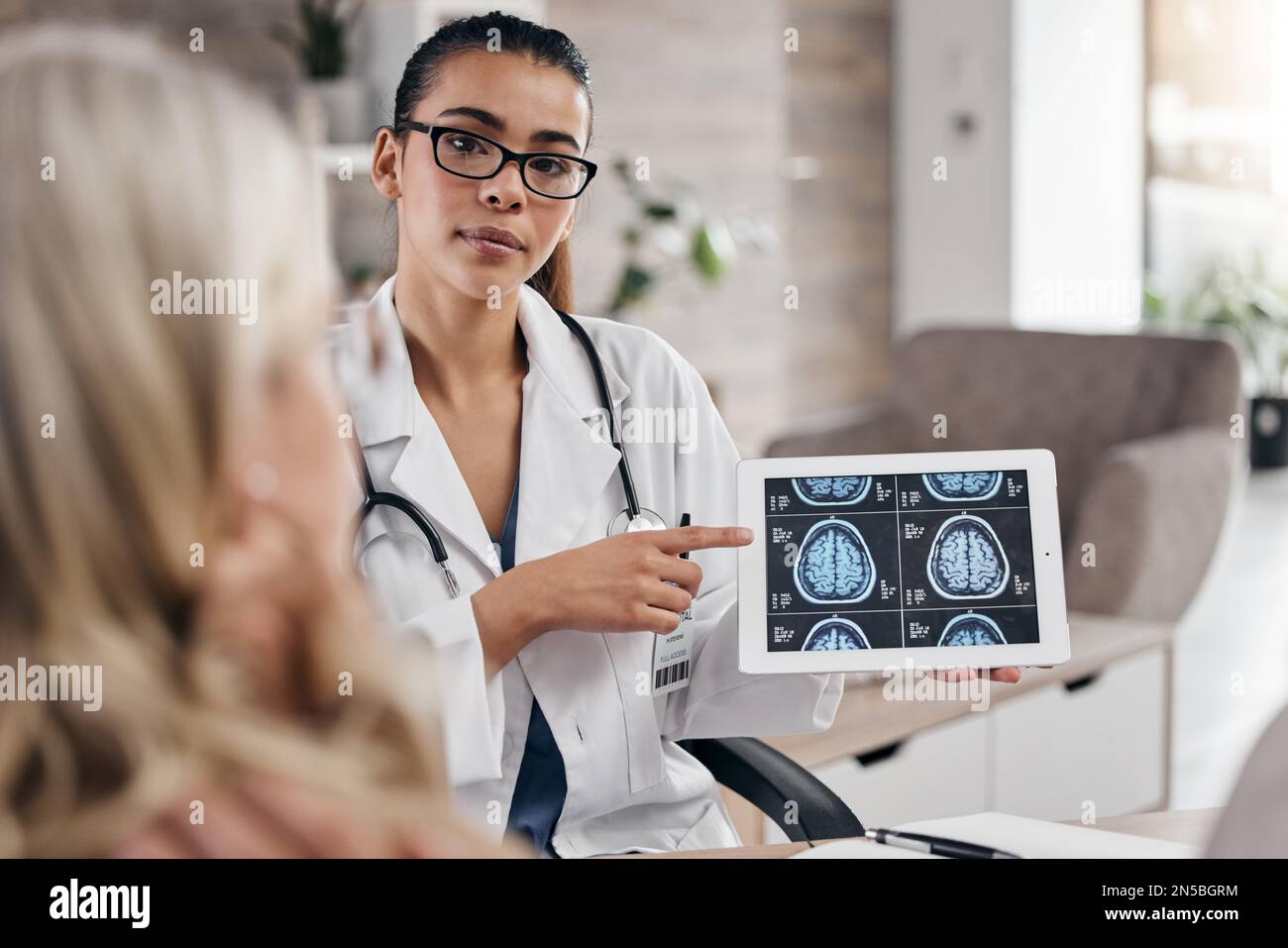 Brain, woman and doctor pointing at tablet, mri scan or xray diagnosis for cancer. Healthcare ...