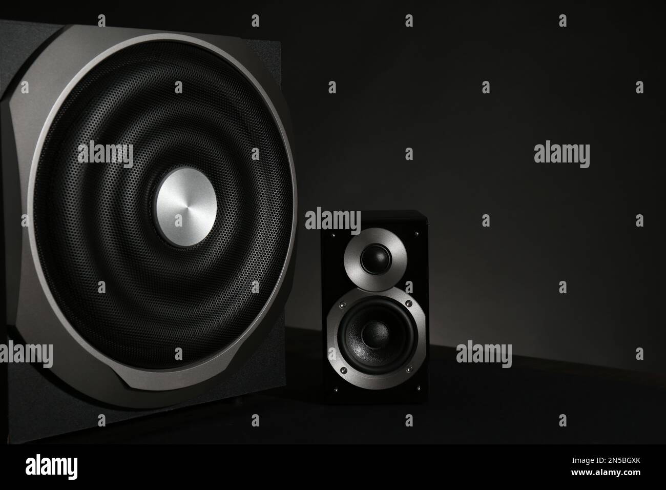 Modern powerful audio speaker and subwoofer on black background. Space ...