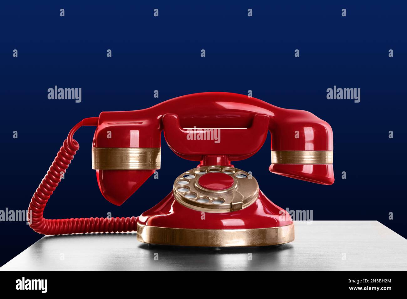 Vintage red corded telephone on table against blue background Stock ...