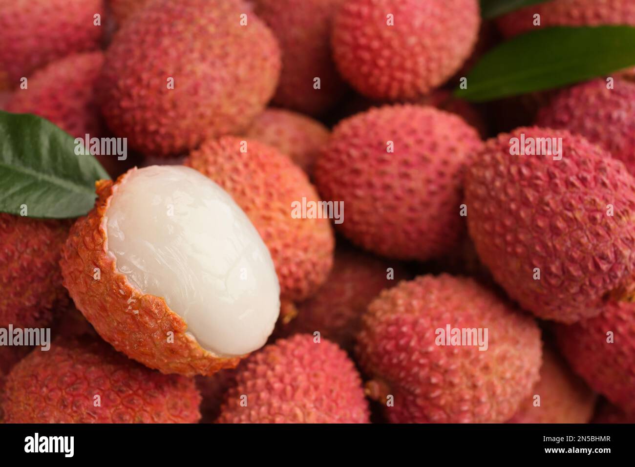 Pile of fresh ripe lychees with leaves as background, closeup Stock ...