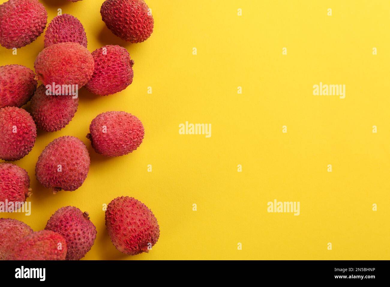 Fresh ripe lychees on yellow background, flat lay. Space for text Stock ...