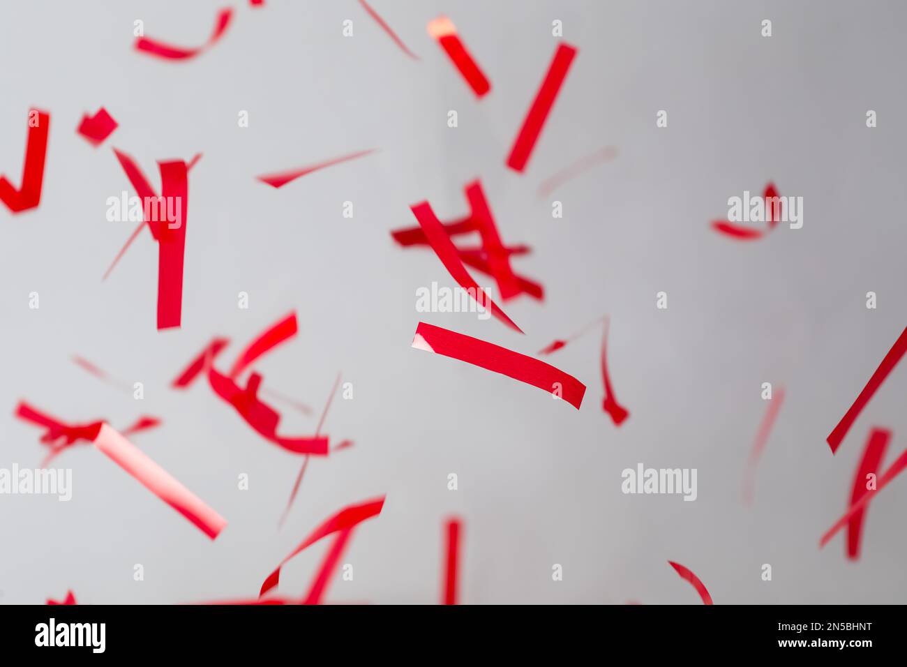 Shiny red confetti falling down on light grey background Stock Photo ...