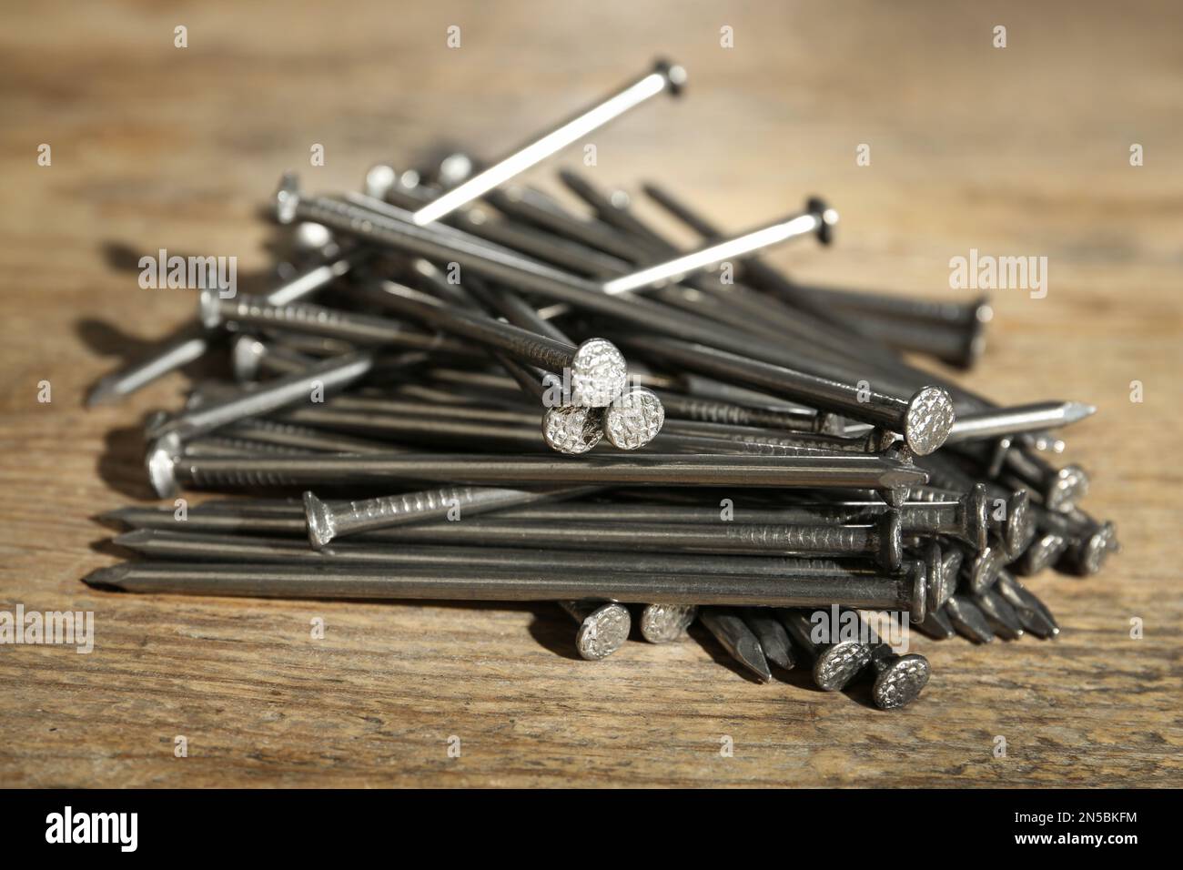 Pile of metal nails on wooden background Stock Photo - Alamy