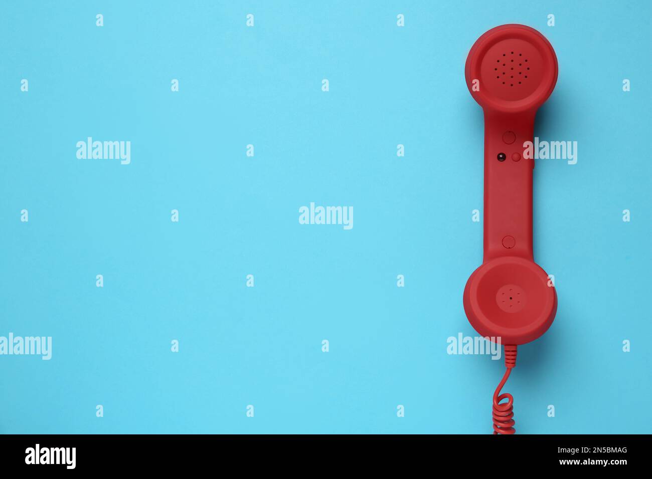Red corded telephone handset on light blue background, top view ...