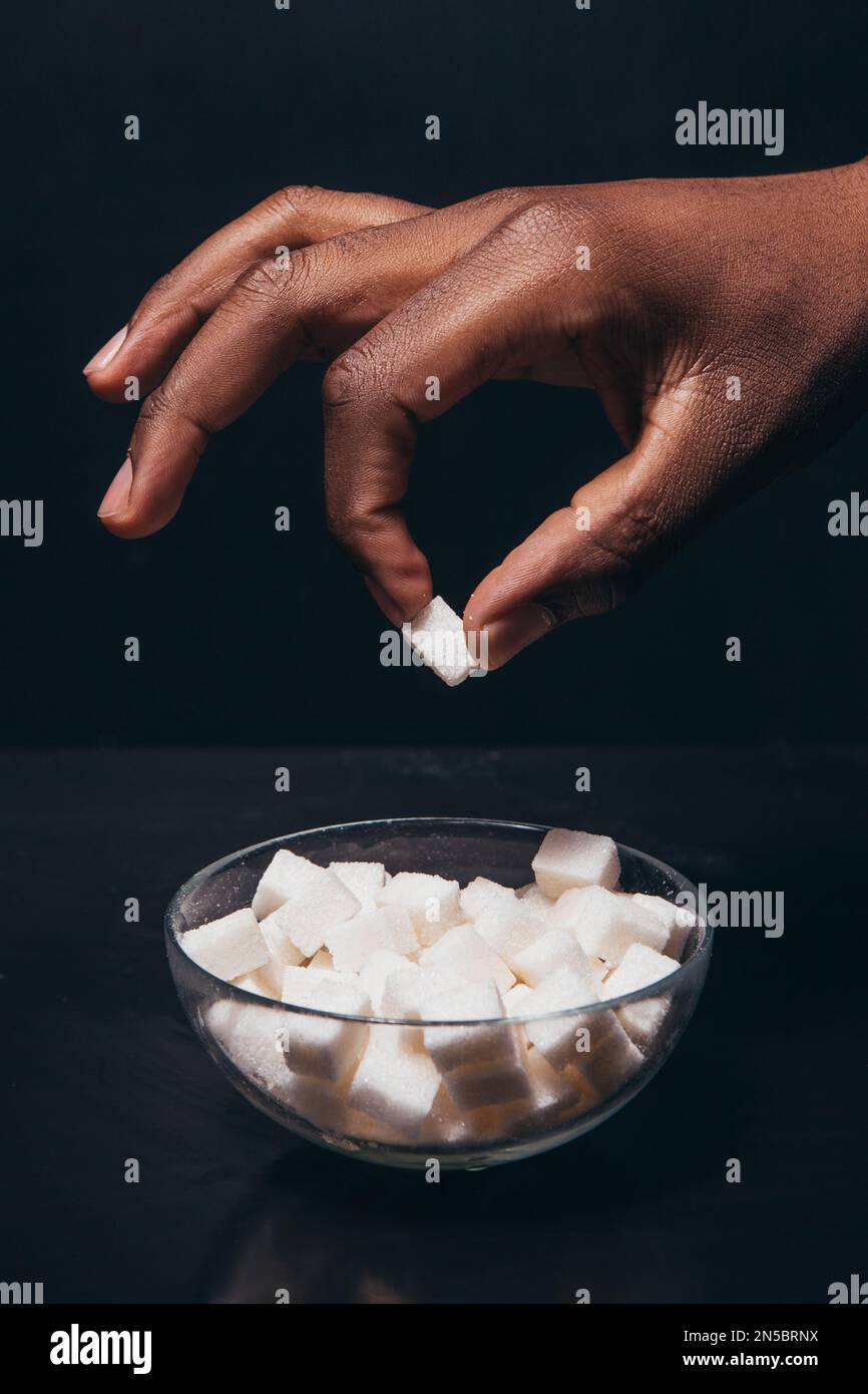 Black man hand with white piece of sugar. Contrast Stock Photo - Alamy