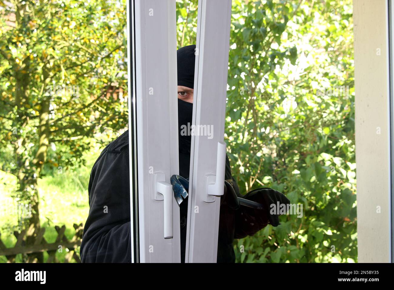 masked burglar with crowbar on a tilted window Stock Photo - Alamy