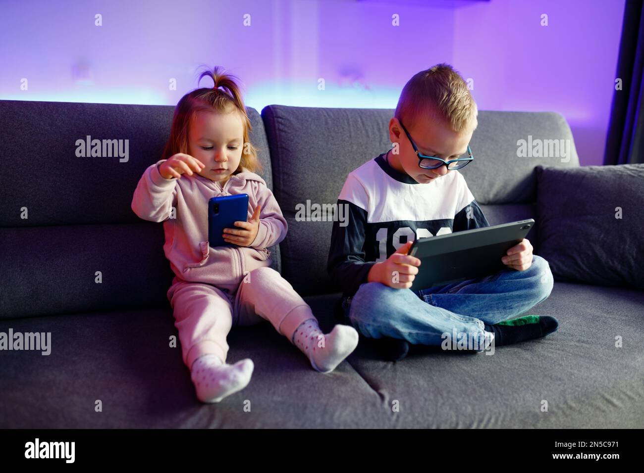 Danya and his sister Emilia play with mobile phones and tablets Stock ...
