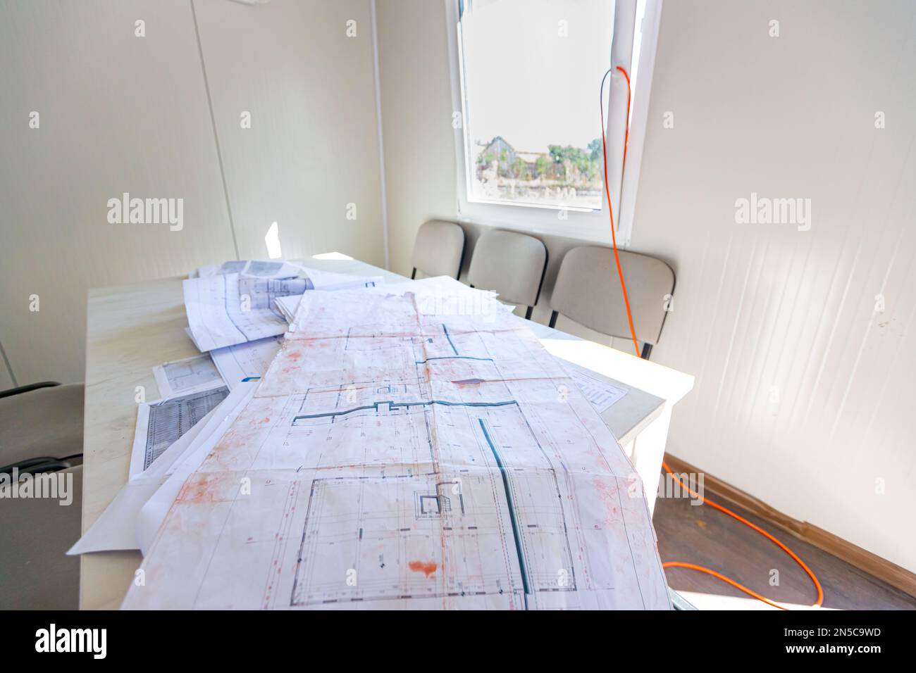 Mason's work desk in office container with pile of messy architectural ...