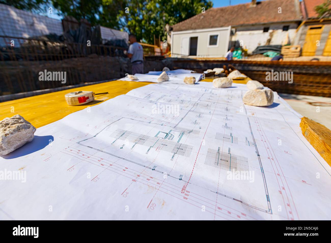 Architectural blueprints, drawings spread out on the improvised table ...