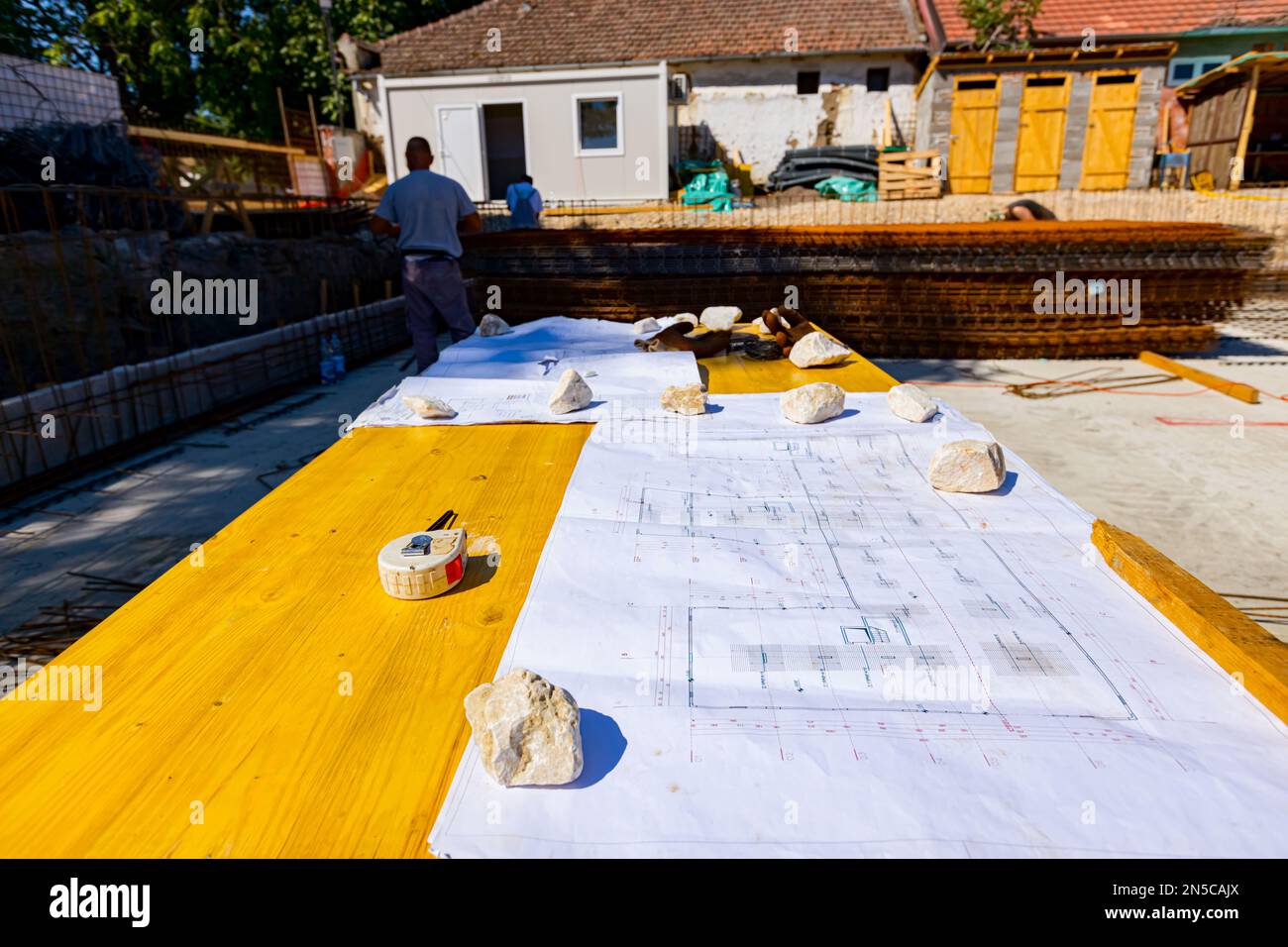 Architectural blueprints, drawings spread out on the improvised table ...