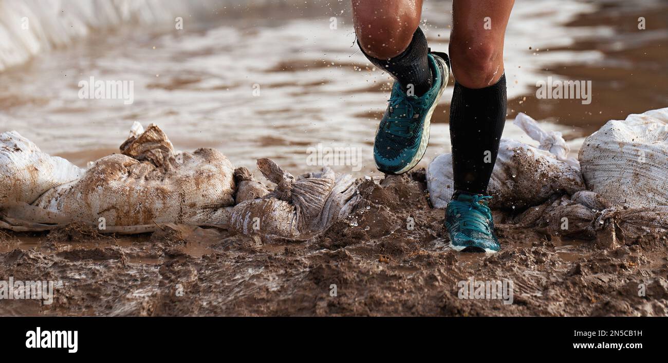 Participant in an obstacle course race runs out of a water obstacle ...