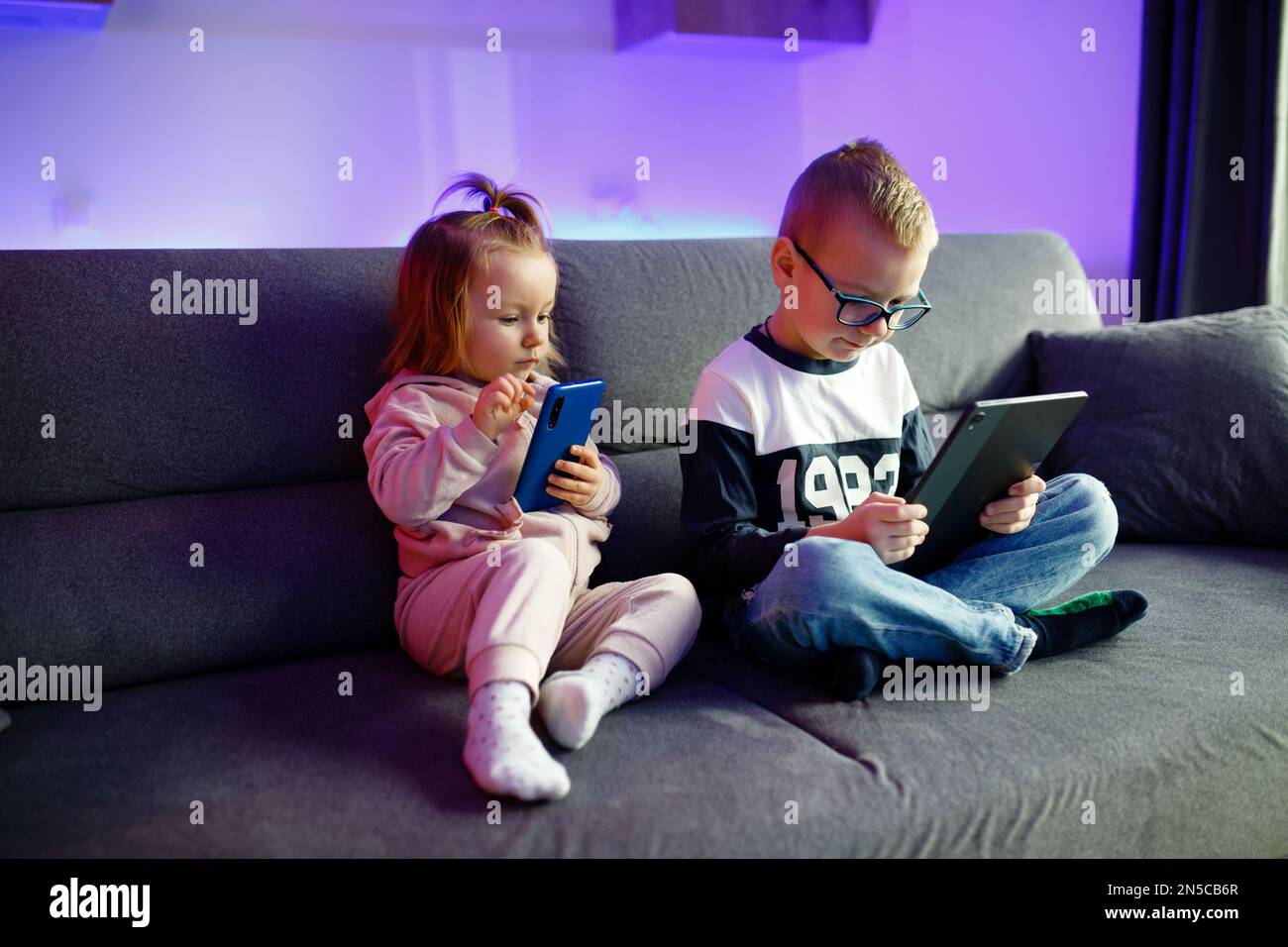 Danya and his sister Emilia play with mobile phones and tablets Stock ...