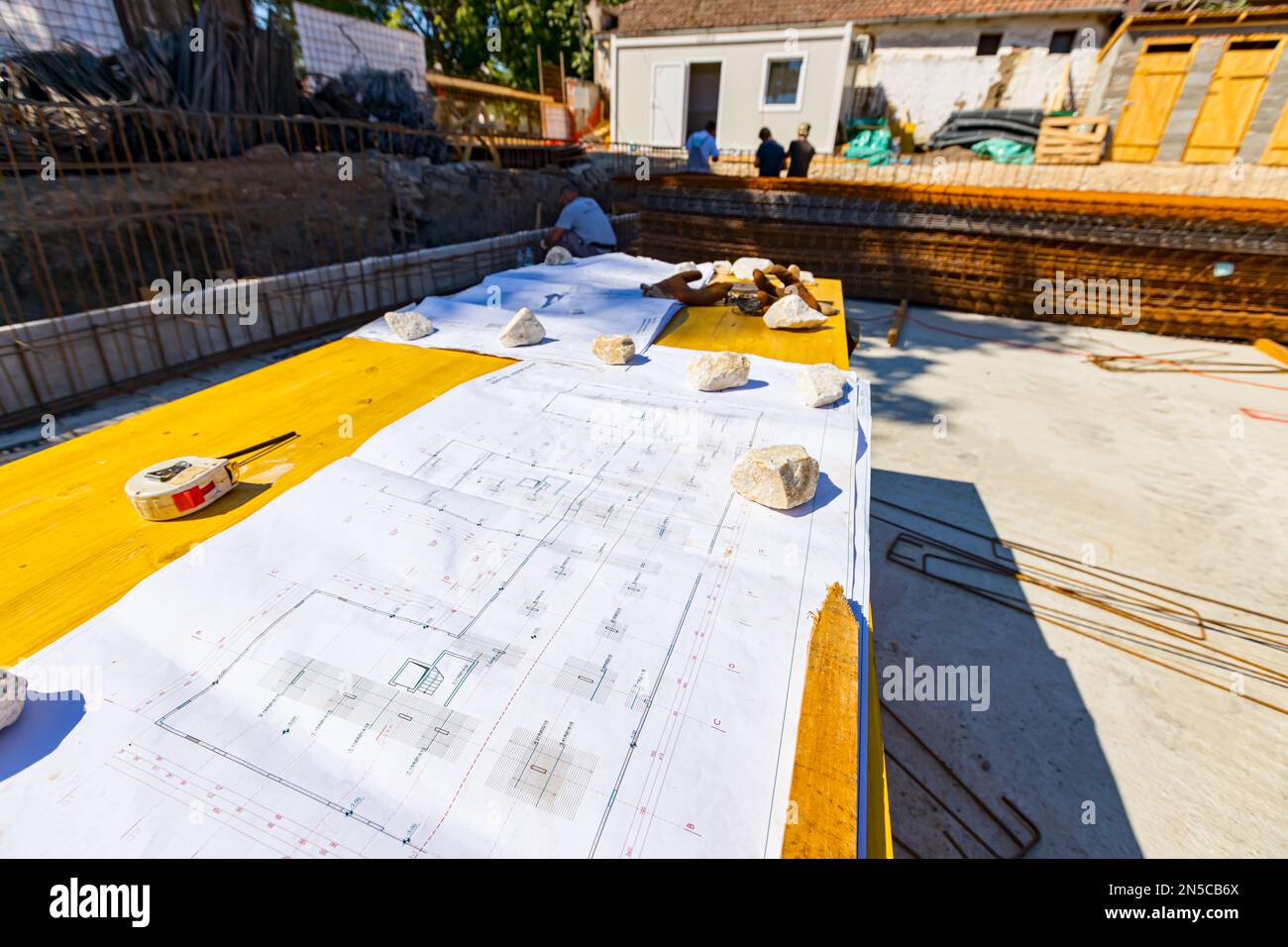 Architectural blueprints, drawings spread out on the improvised table ...