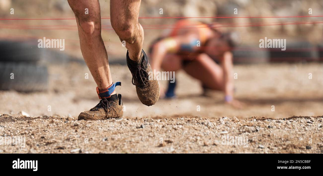 Mud race runners. Crawling,passing under a barbed wire obstacles during ...