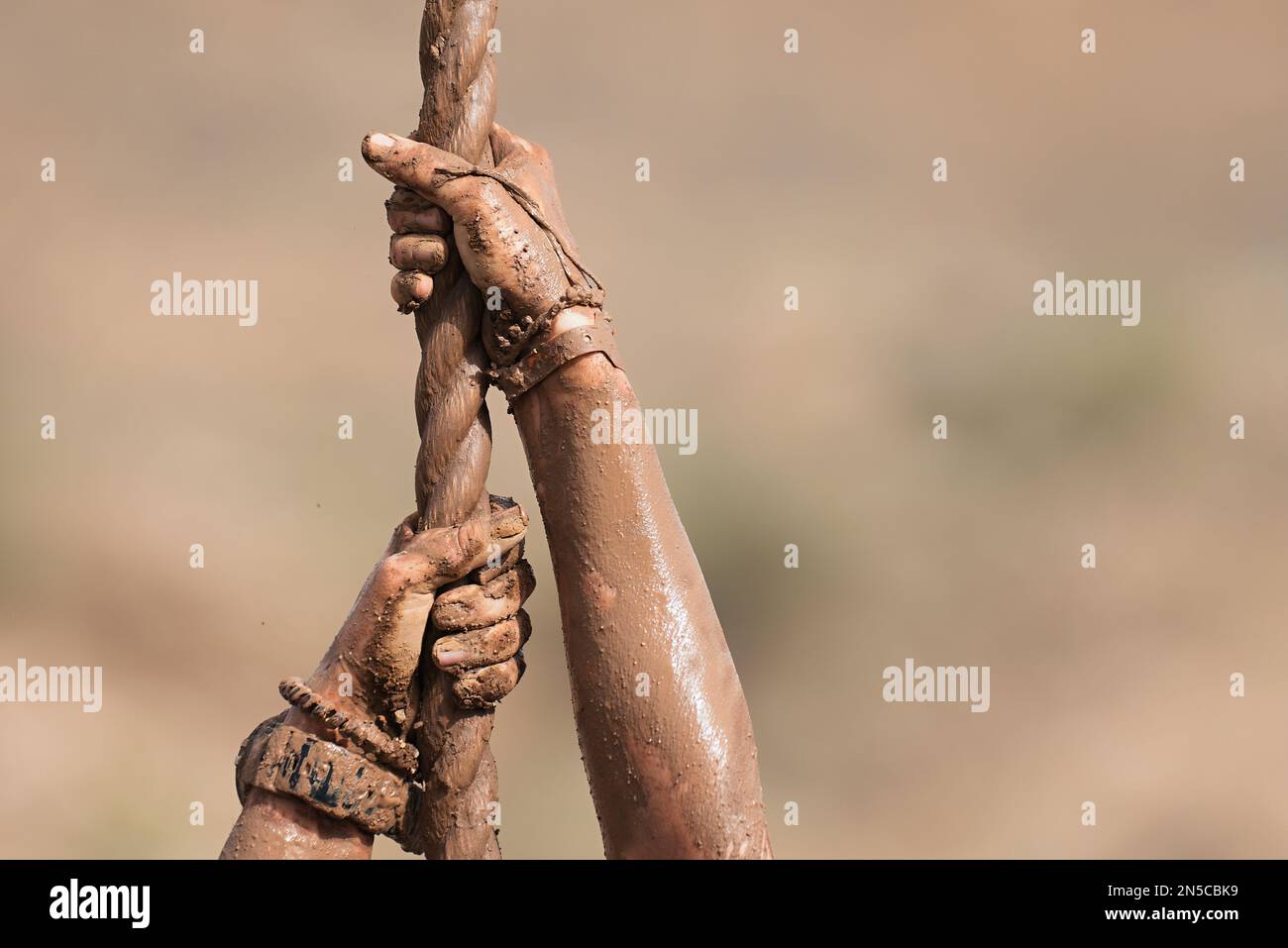 Mud race runner. Detail of muddy hands they climb the rope. Athletic ...