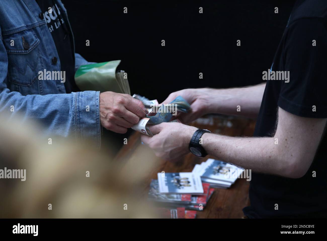 man buying concert merchandise and exchanging money Stock Photo - Alamy