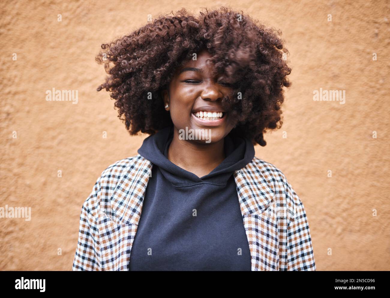 Black woman, smile and happy young person by an orange wall feeling ...