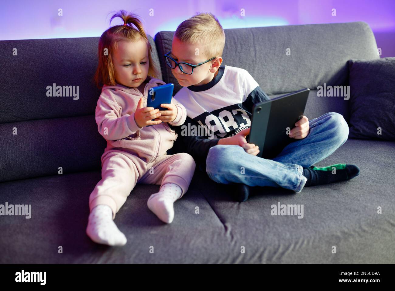 Danya and his sister Emilia play with mobile phones and tablets Stock ...