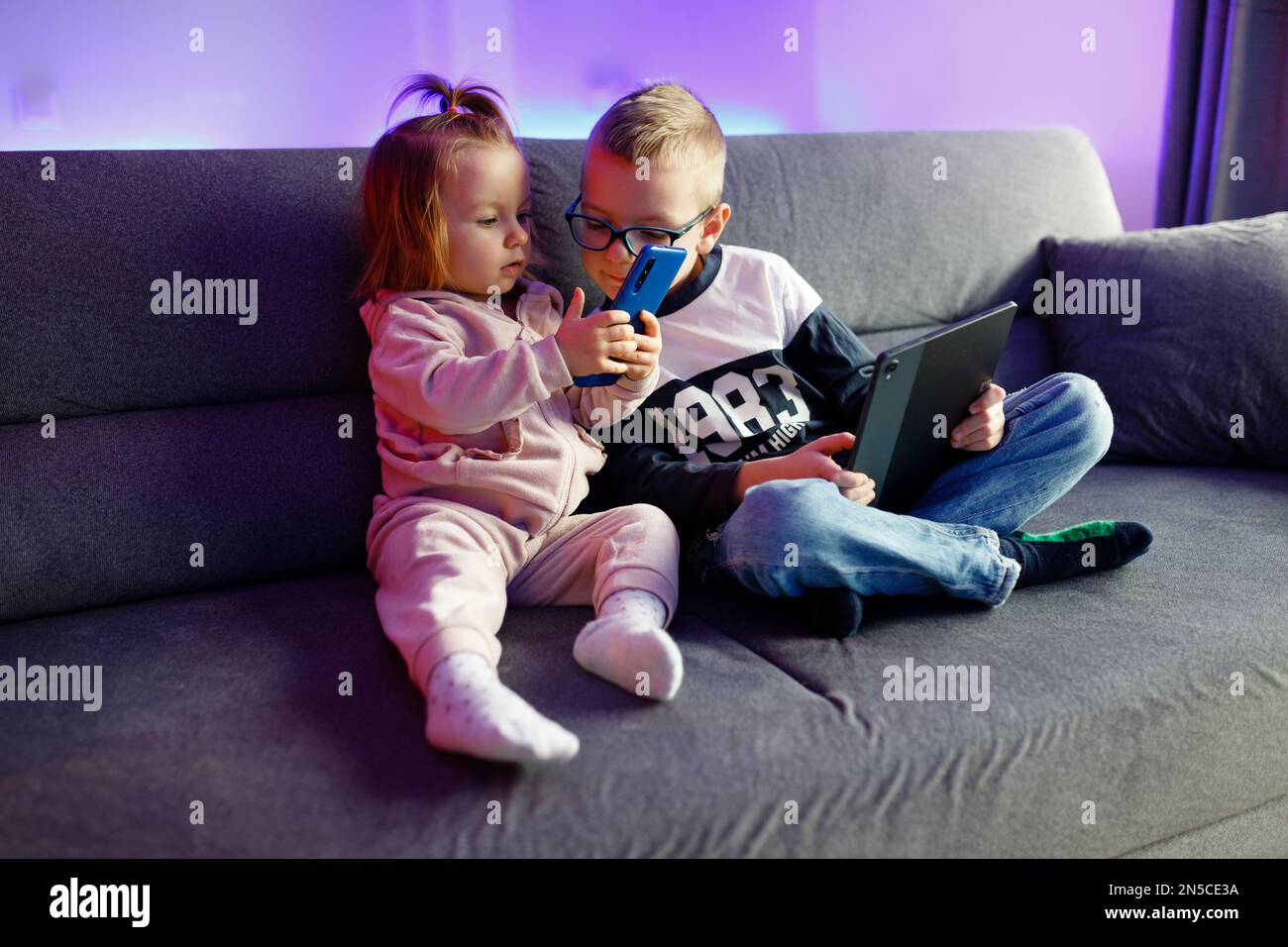 Danya and his sister Emilia play with mobile phones and tablets Stock ...