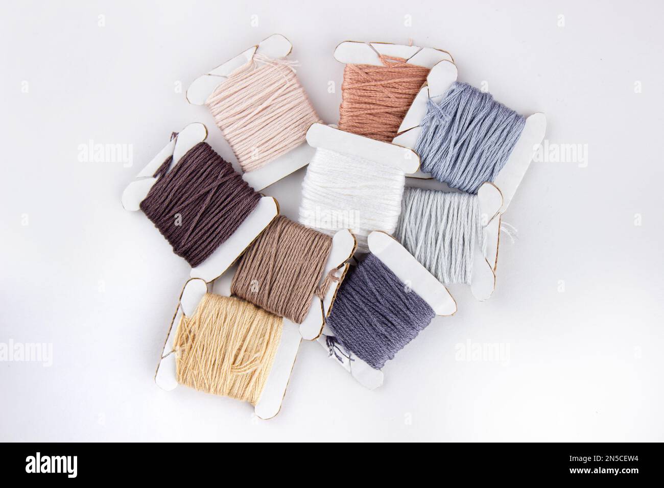 Skeins of cotton threads of different colors lie in a pile on a white ...