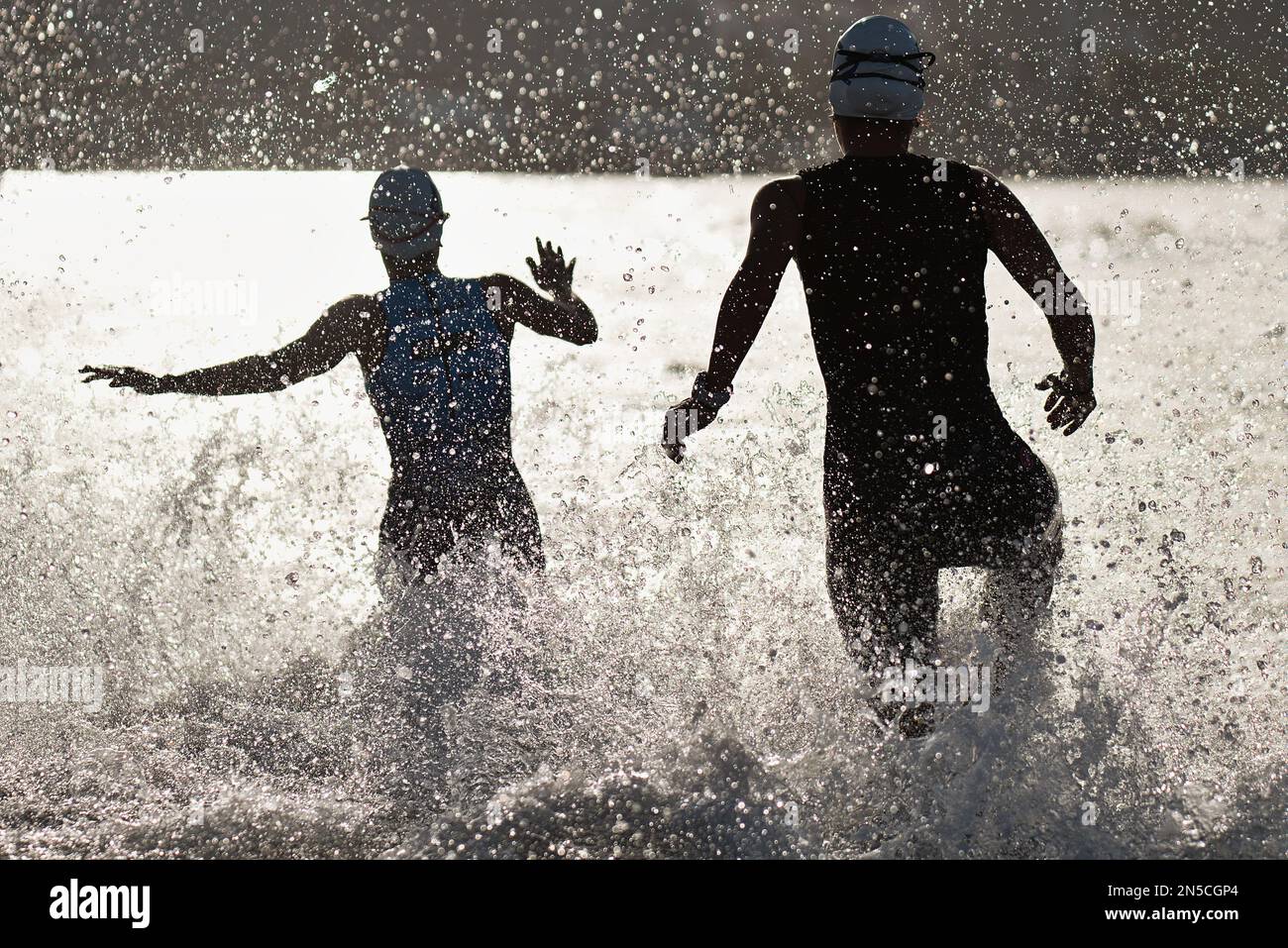Silhouette of two female runners running into the water. Image of ...