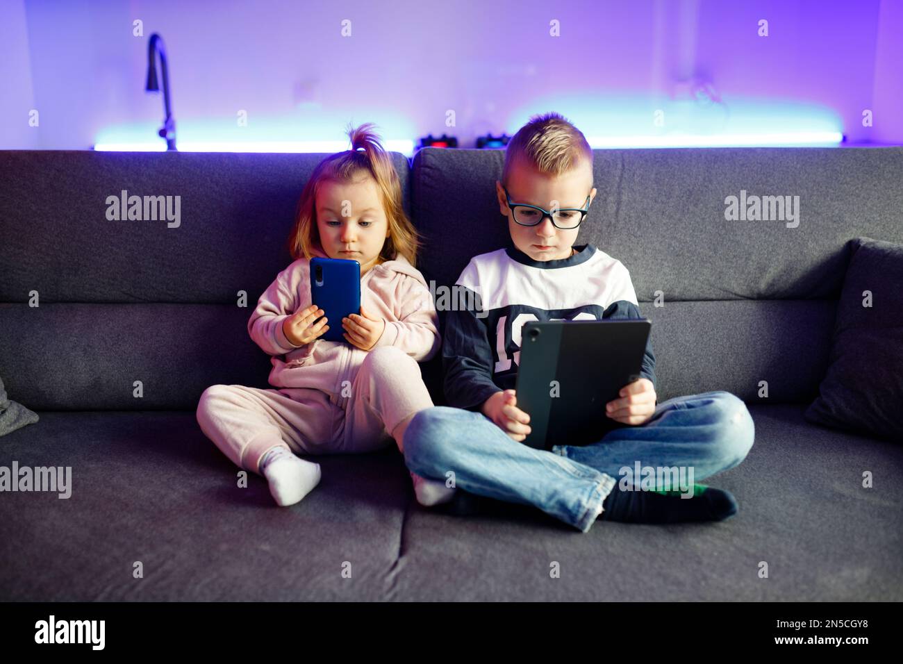 Danya and his sister Emilia play with mobile phones and tablets Stock ...