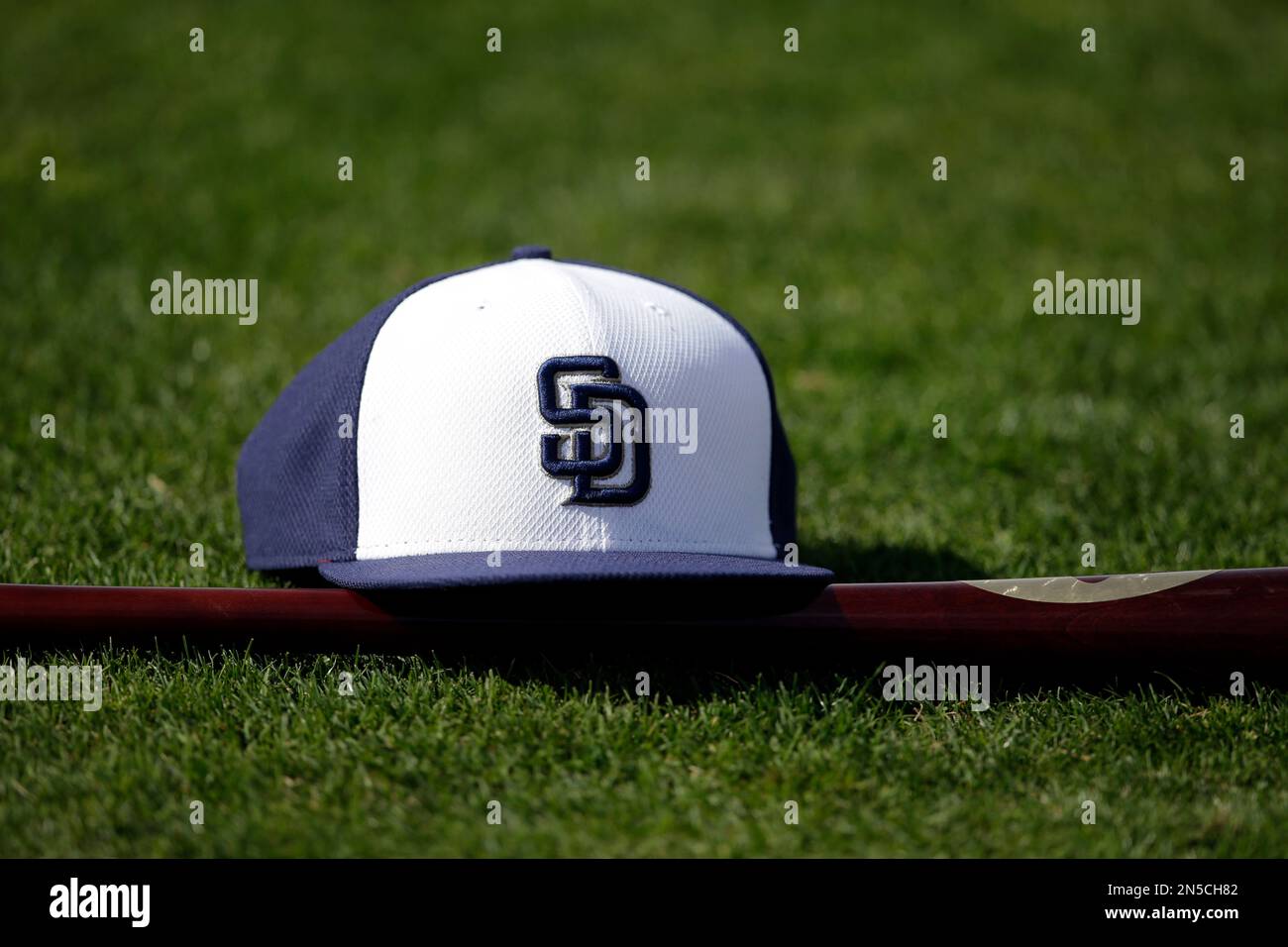 A San Diego Padres ball cap sits on a bat on a practice field as the ...