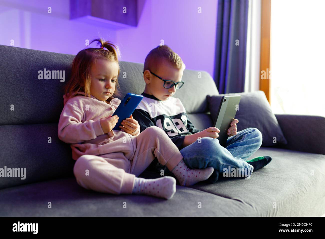 Danya and his sister Emilia play with mobile phones and tablets Stock ...