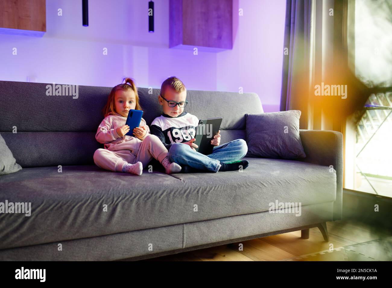 Danya and his sister Emilia play with mobile phones and tablets Stock ...