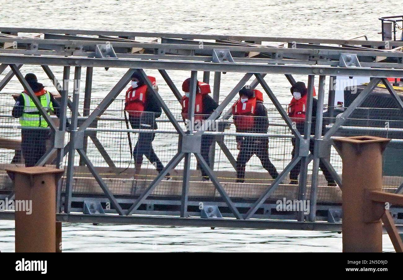 A group of people thought to be migrants walk through the immigration ...