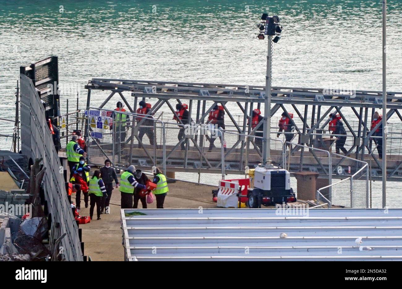 A group of people thought to be migrants walk through the immigration ...