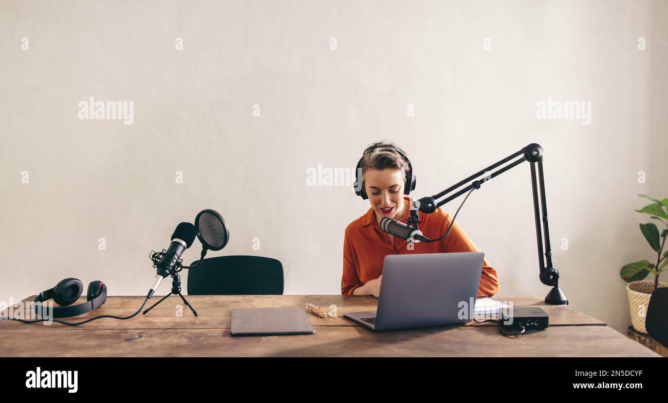 Female radio dj preparing a live audio broadcast with a laptop. Woman ...