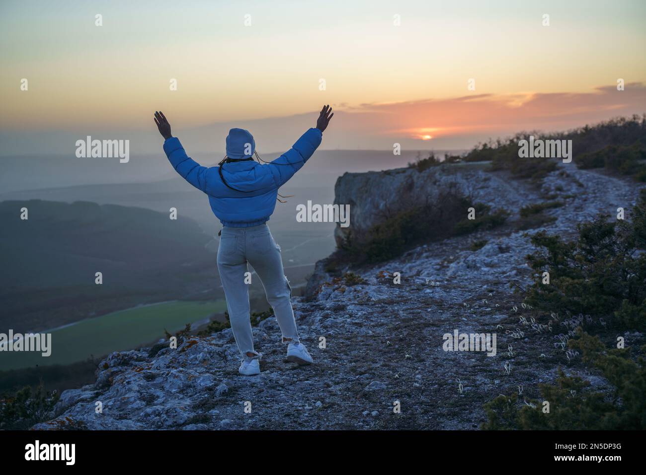 Woman hiker open arms on top of sunrise mountain. The girl salutes the ...