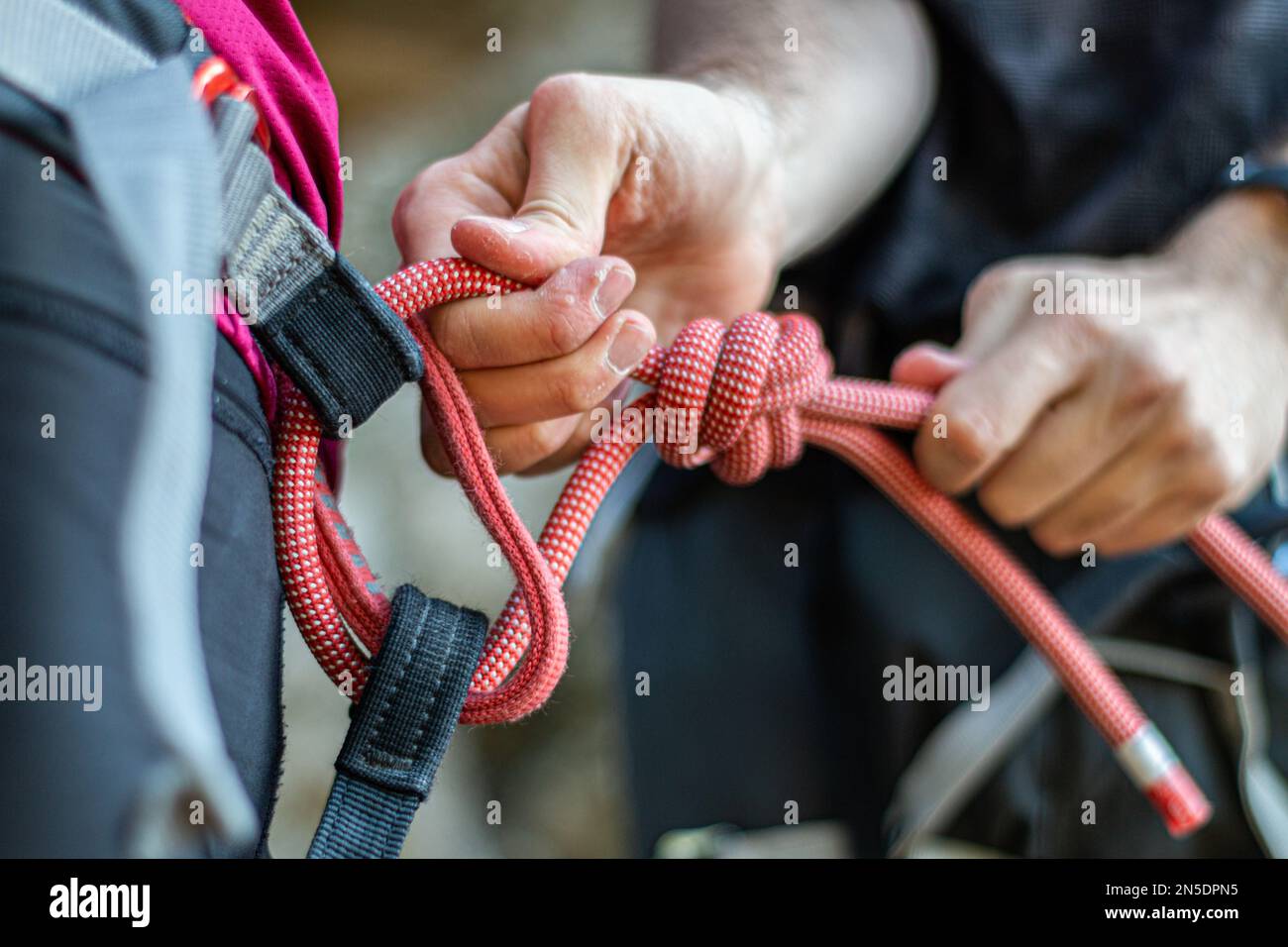 An alpinist tying a rope on his climbing equipment Stock Photo - Alamy