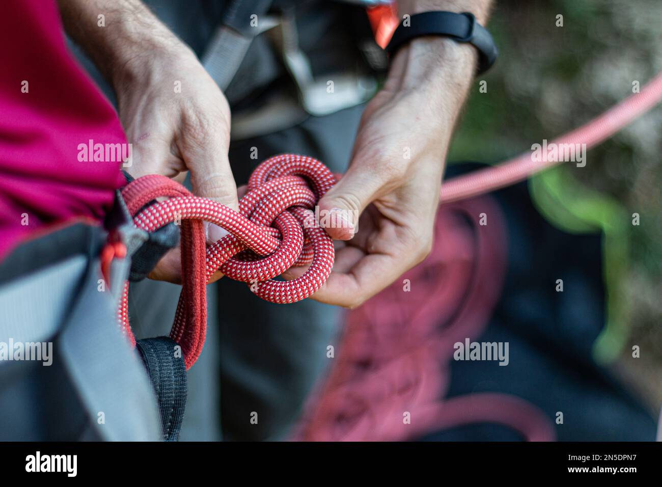 An alpinist tying a rope on his climbing equipment Stock Photo - Alamy